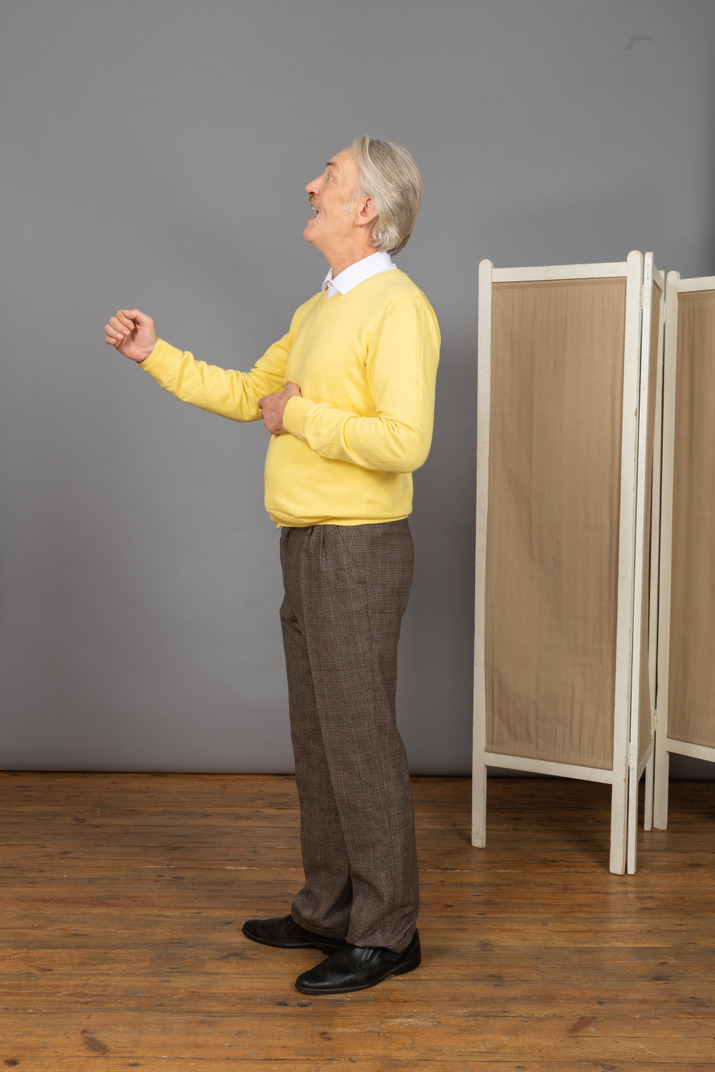 Side view of an inspired old man raising his hand Photo