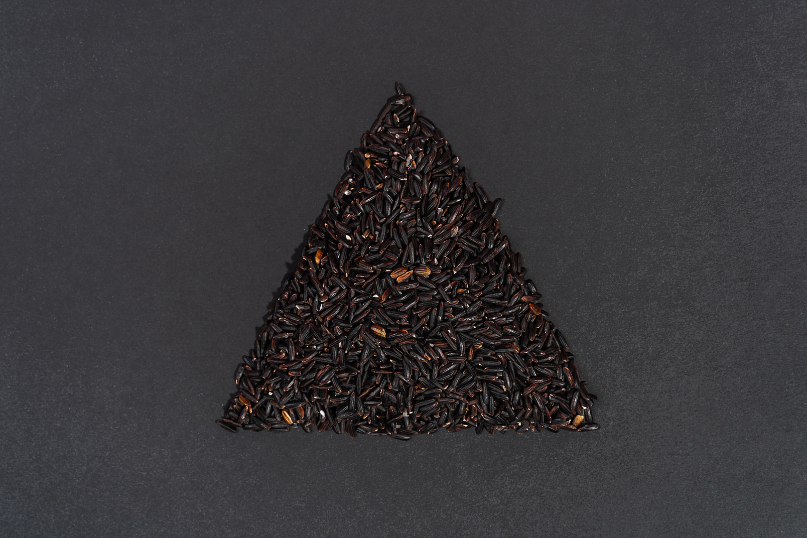 Black rice shaped in a triangle on black background Photo