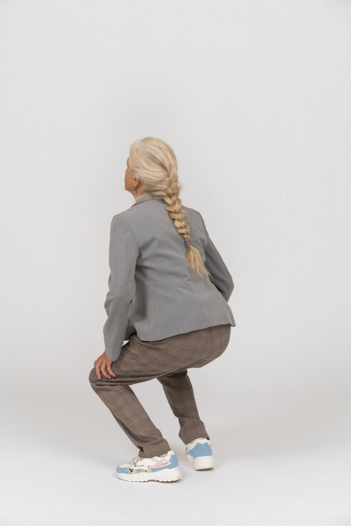 Back view of an old lady in suit squatting Photo