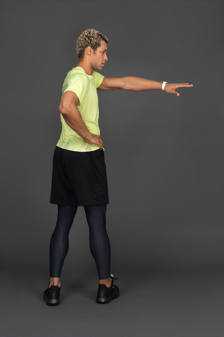 Back view of a dark-skinned young man turning right and outstretching ...