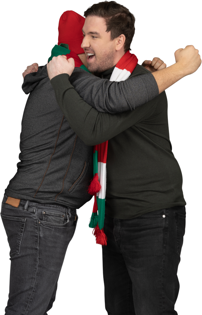 Side view of two emotional hugging male football fans clenching fists Photo
