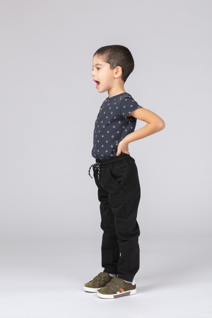 Side view of a cute kid boy standing with hands on hips Photo