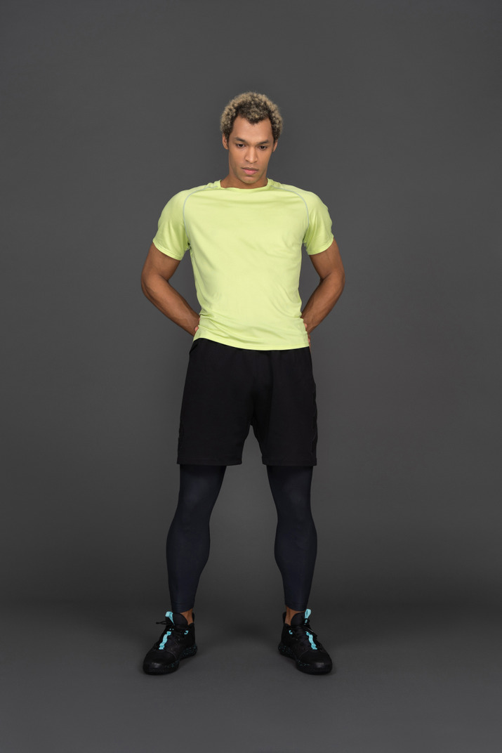 Front view of a dark-skinned young man putting hands on lower back Photo