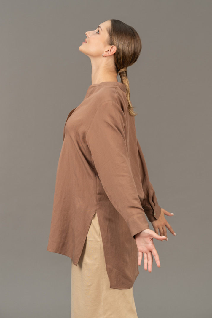 Side view of a woman looking up with arms wide open Photo