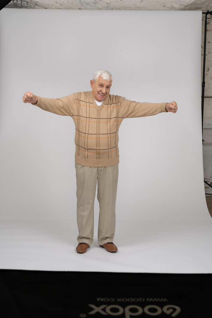 Front view of a happy old man in casual clothes standing with ...