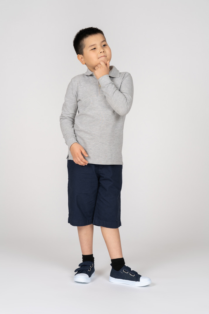 Little boy touching his chin Photo
