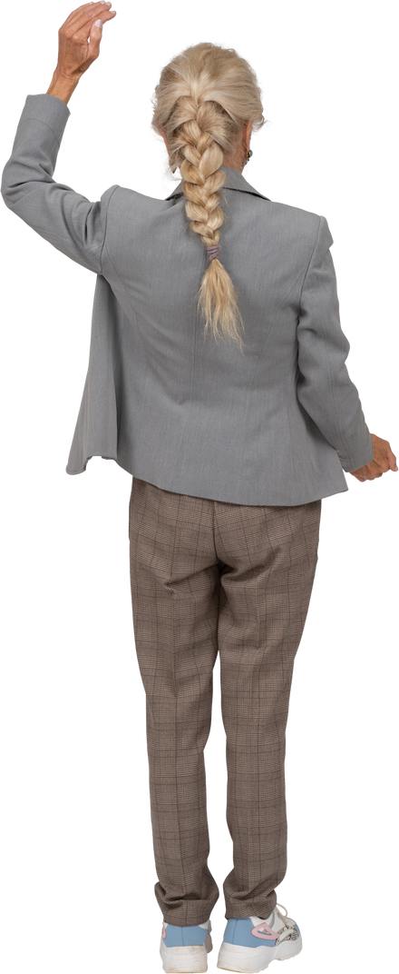 Rear view of an old lady in suit standing with raised arm Photo