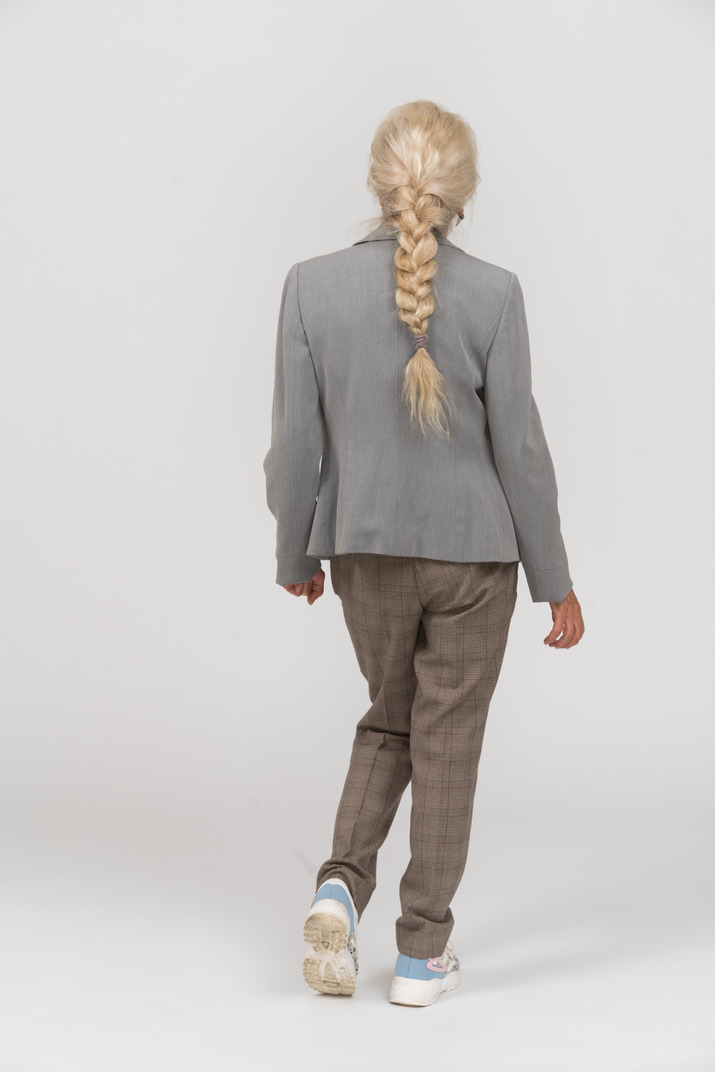 Back view of an old lady in suit posing on one leg Photo